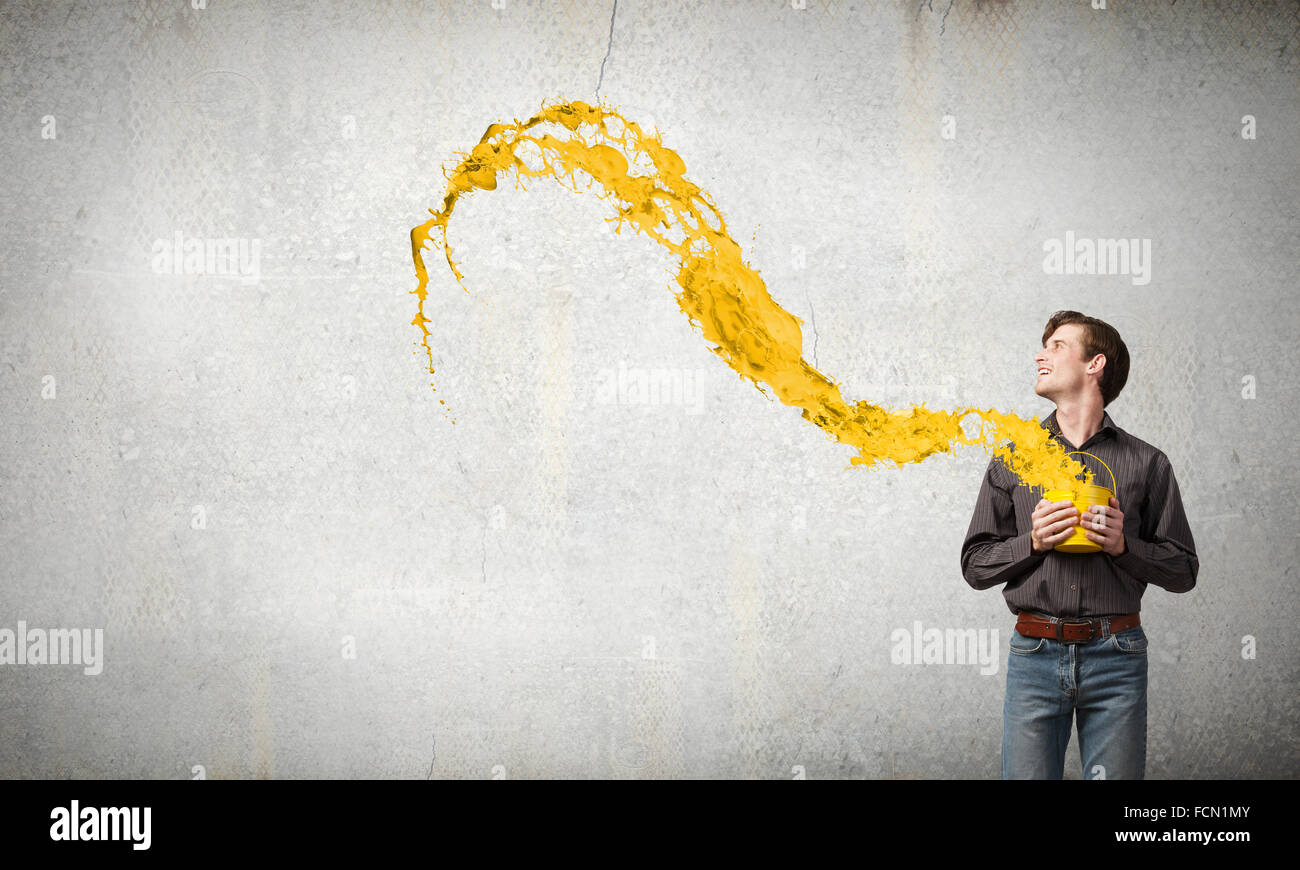 Young man in casual splashing paint from bucket Stock Photo - Alamy