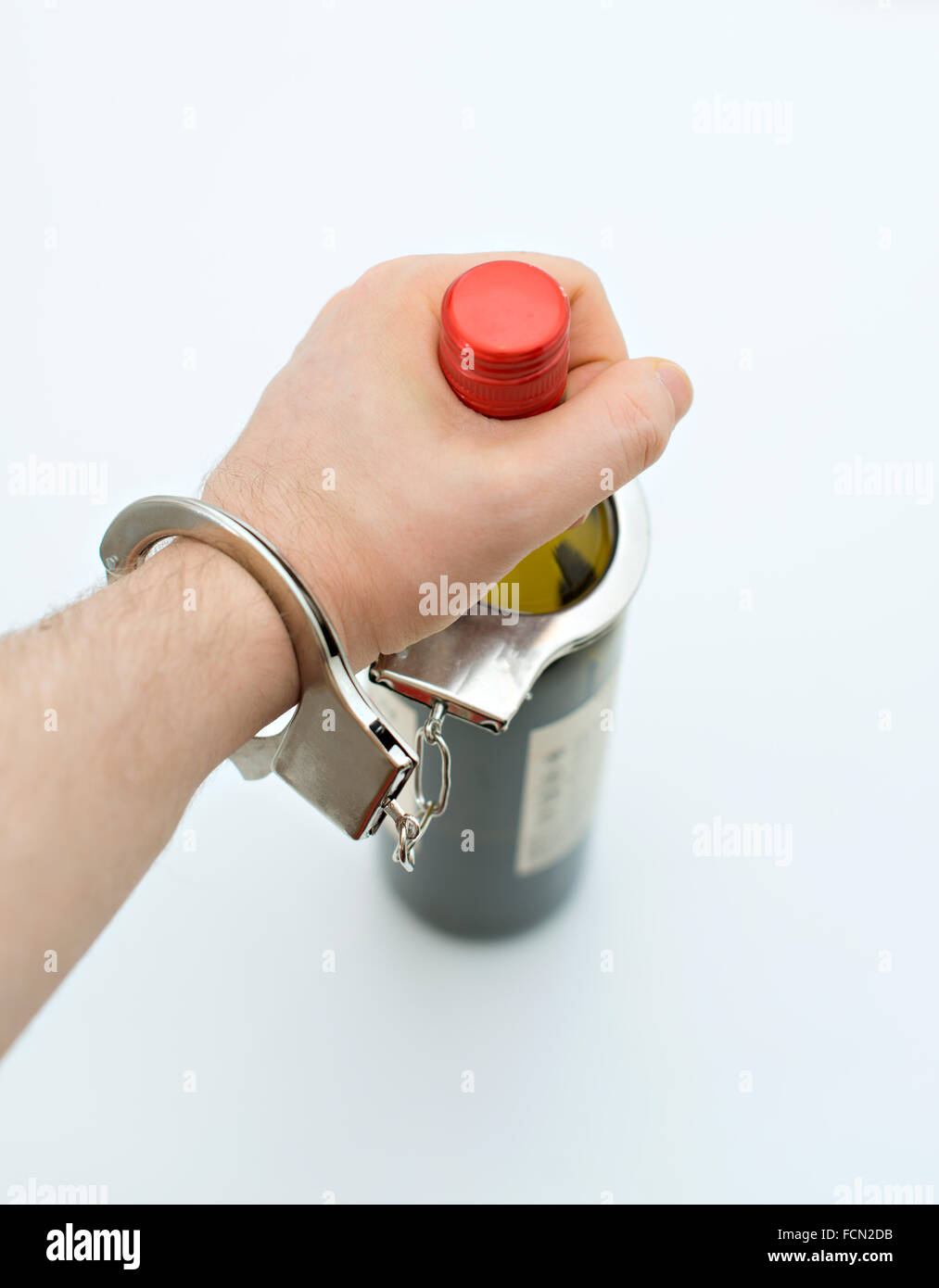 Hand handcuffed to bottle of wine. Alcoholism concept. Space for text ...
