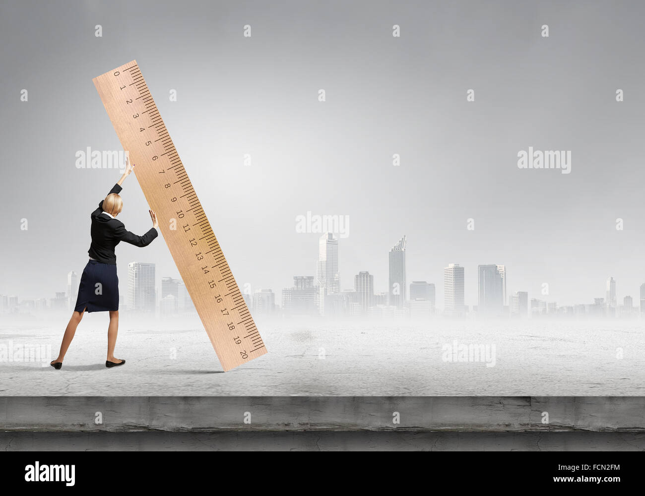 Young businesswoman measuring something with big ruler Stock Photo - Alamy