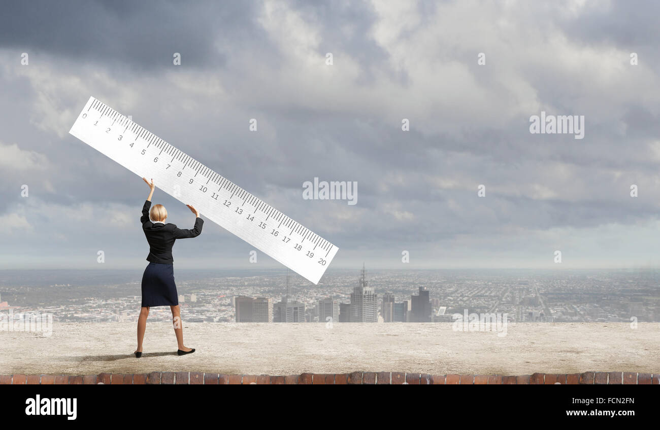Young businesswoman measuring something with big ruler Stock Photo - Alamy