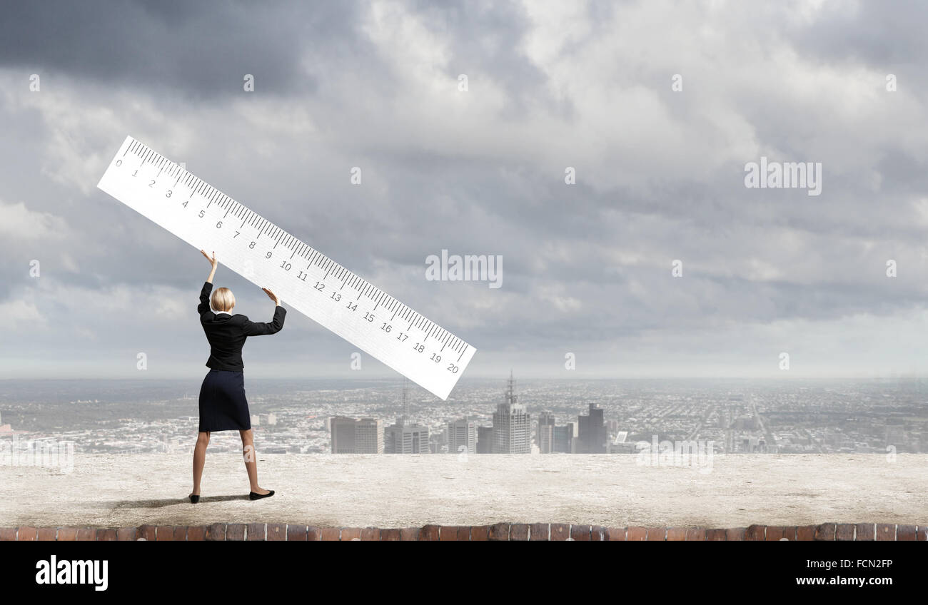 Young businesswoman measuring something with big ruler Stock Photo - Alamy