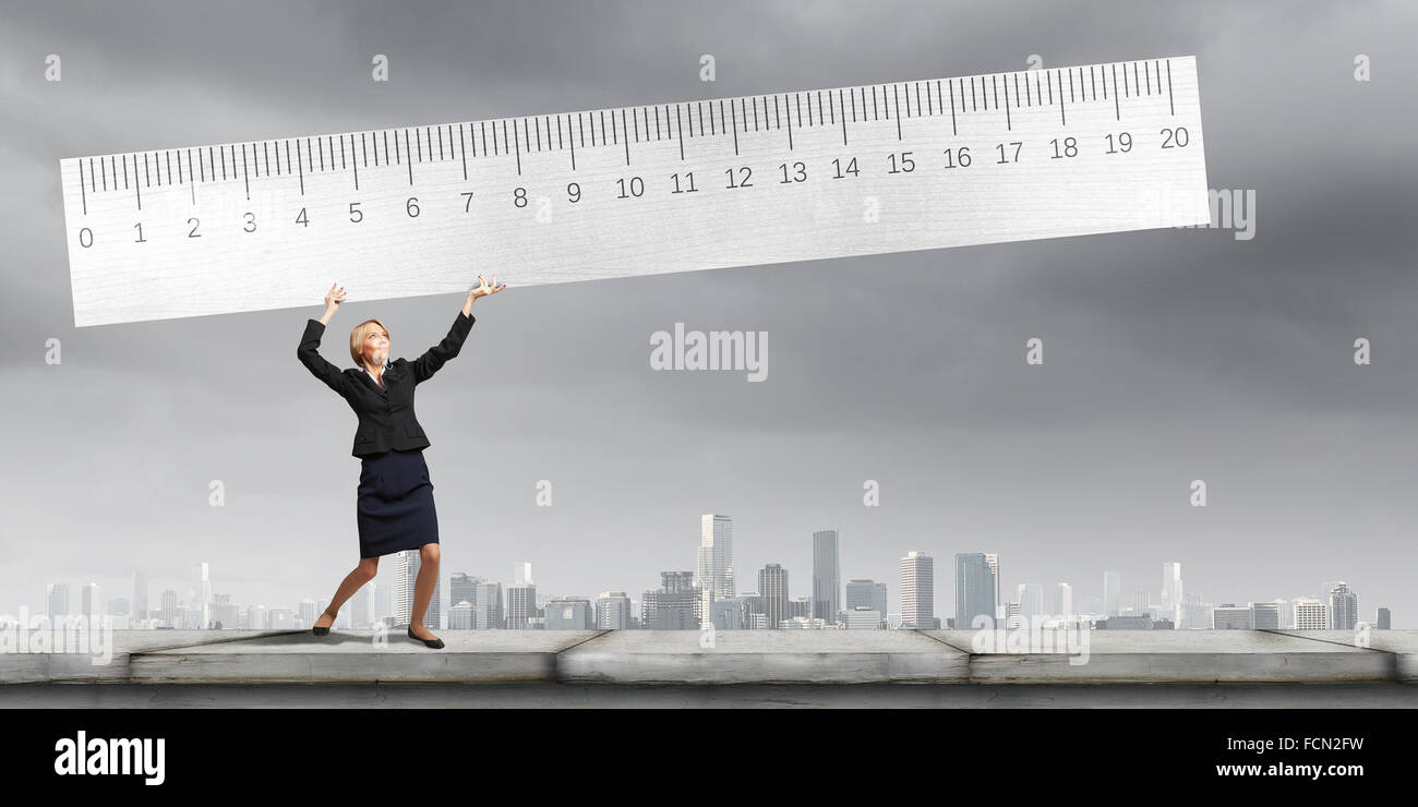 Young businesswoman measuring something with big ruler Stock Photo - Alamy