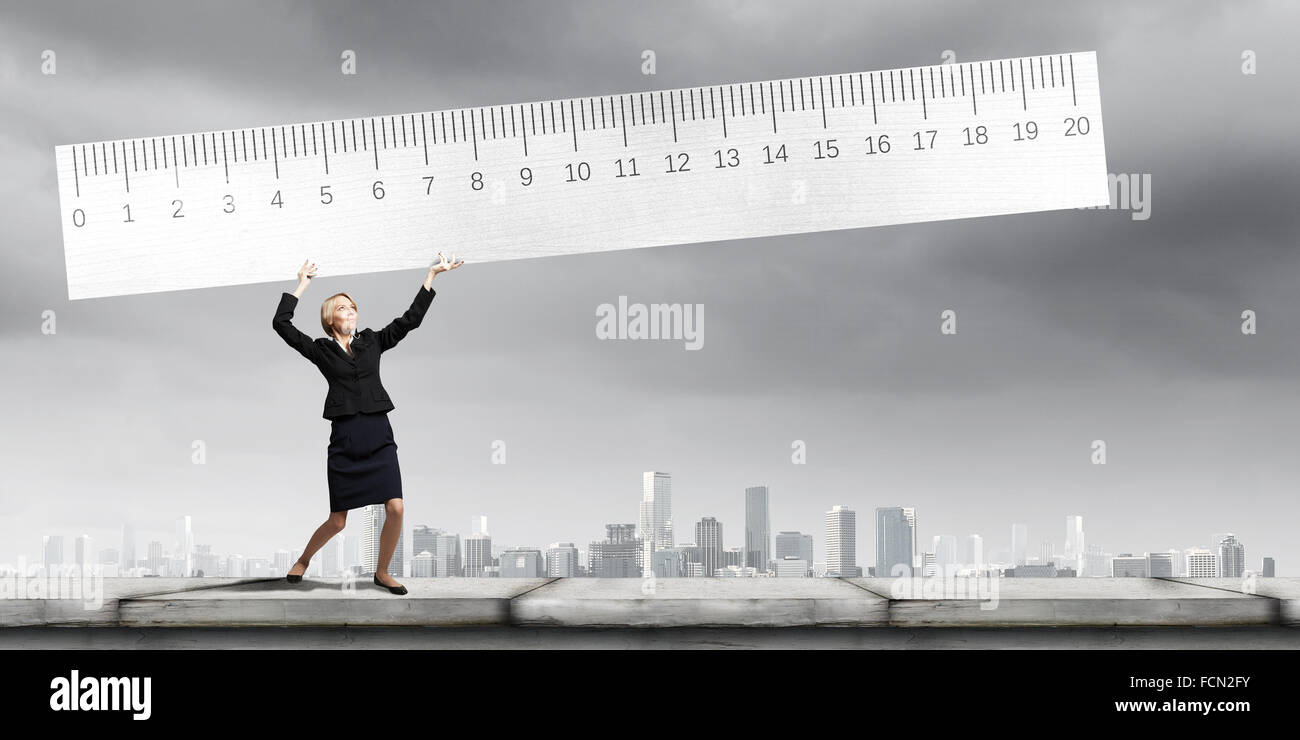 Young businesswoman measuring something with big ruler Stock Photo - Alamy
