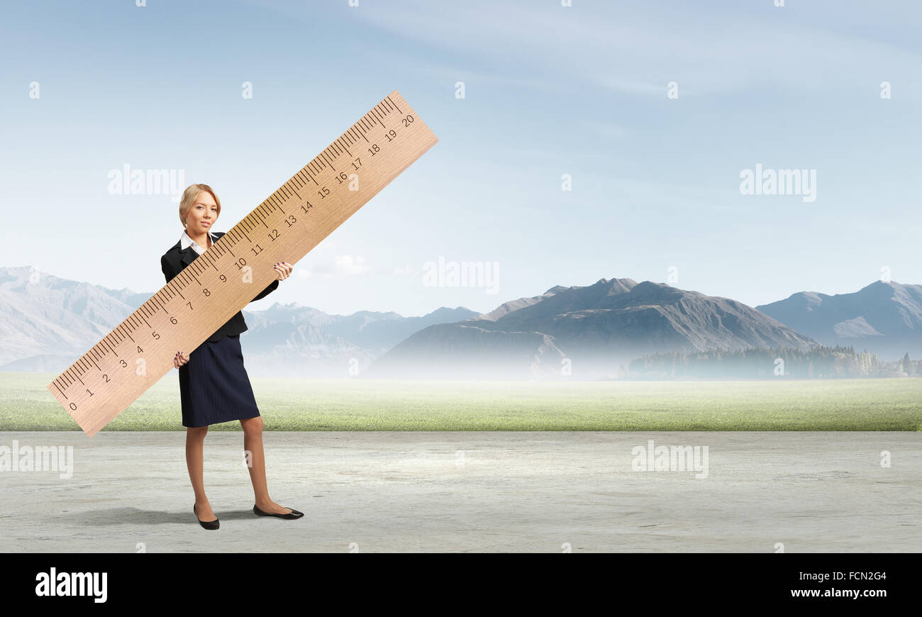 Young businesswoman measuring something with big ruler Stock Photo - Alamy