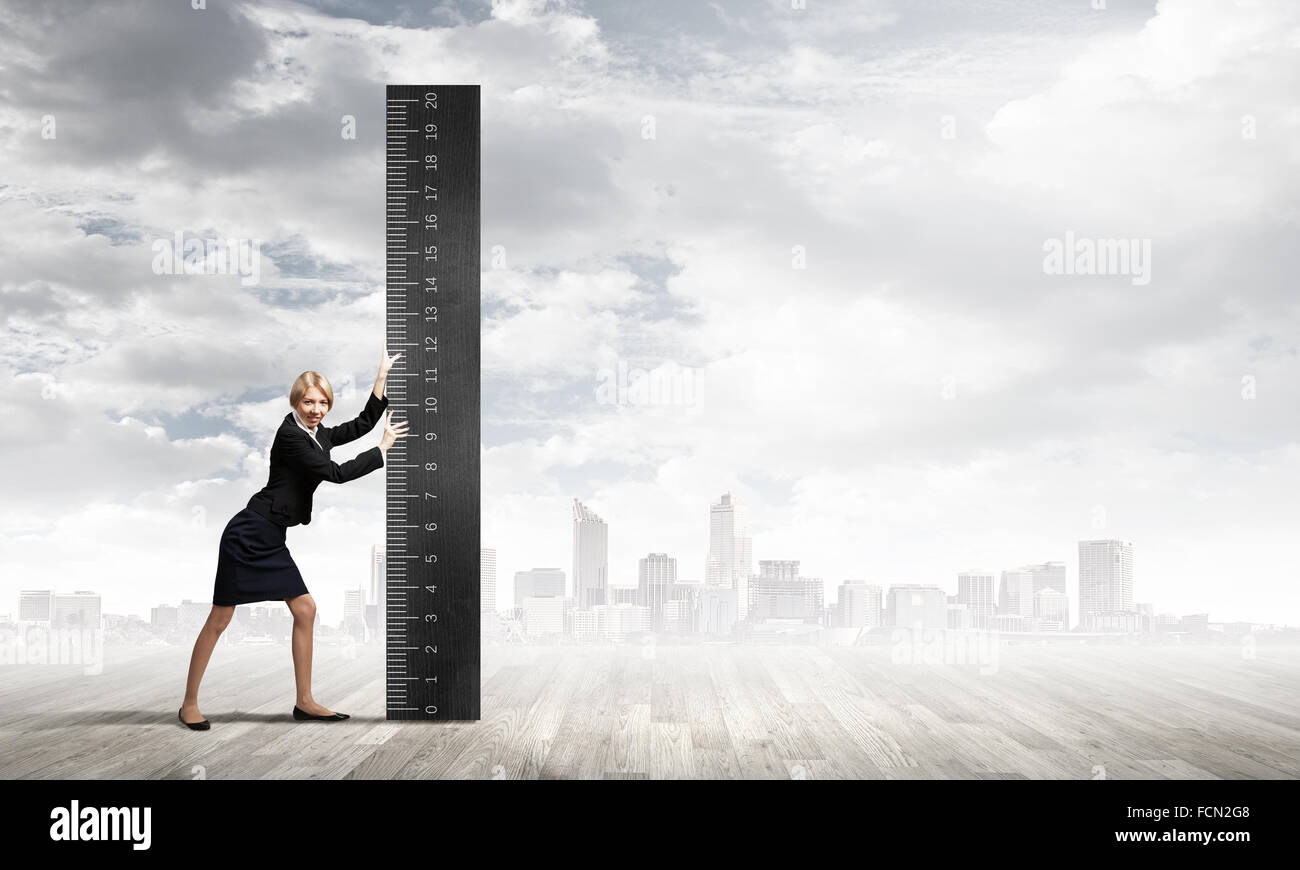 Young businesswoman measuring something with big ruler Stock Photo - Alamy