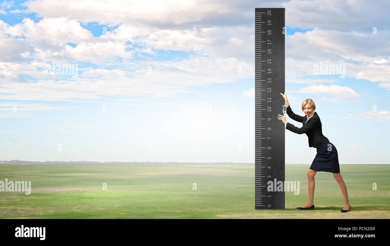 Young businesswoman measuring something with big ruler Stock Photo - Alamy