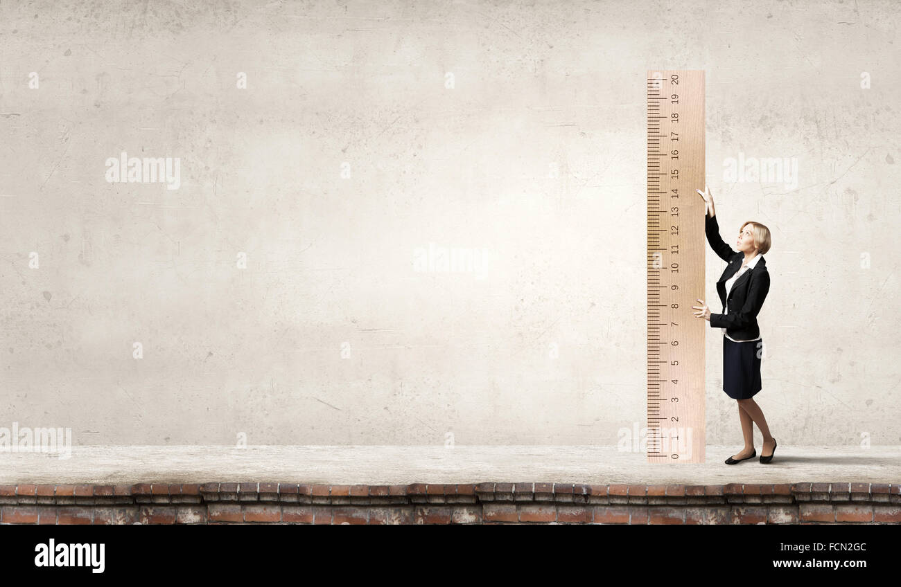 Young businesswoman measuring something with big ruler Stock Photo - Alamy