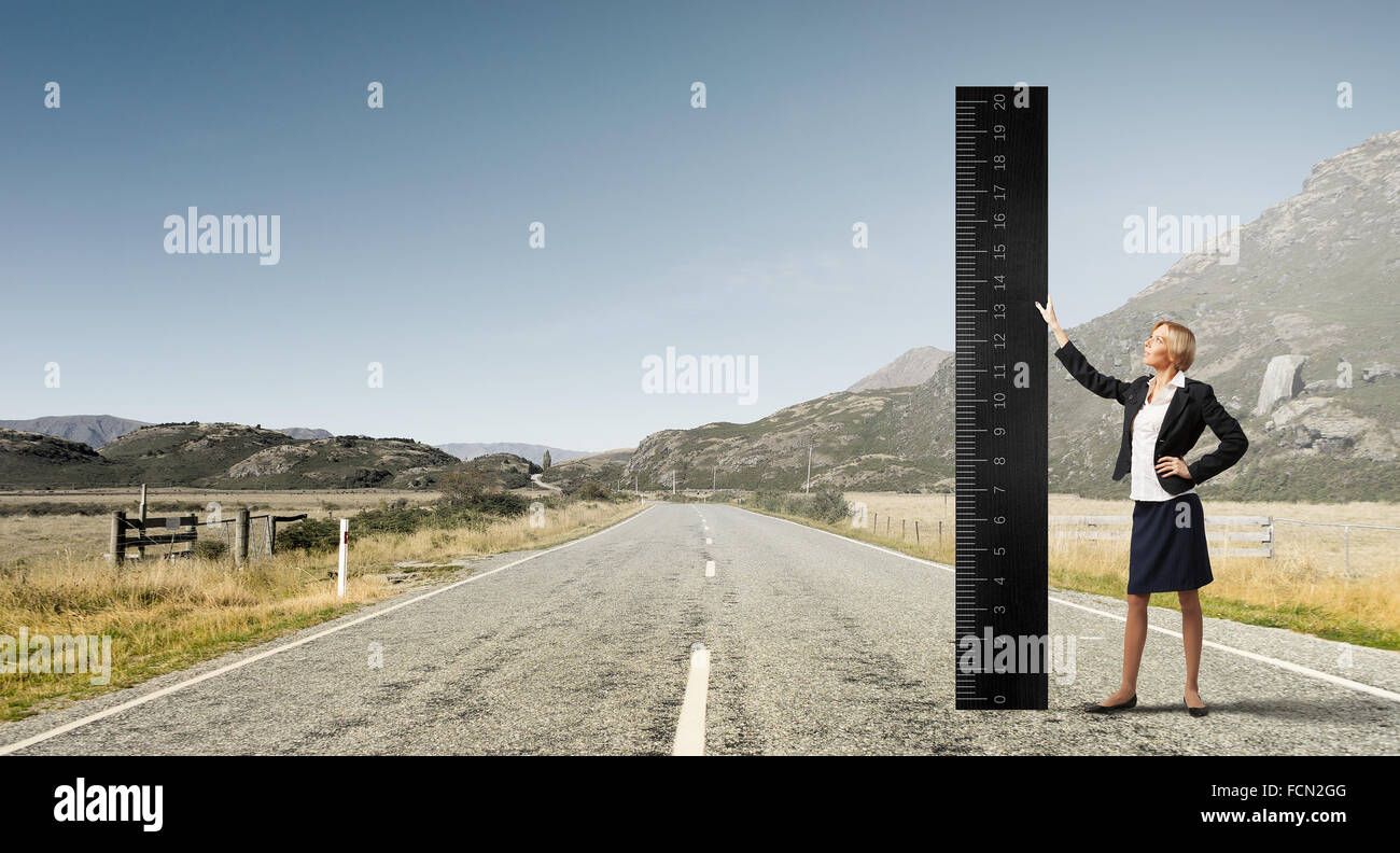 Young businesswoman measuring something with big ruler Stock Photo - Alamy