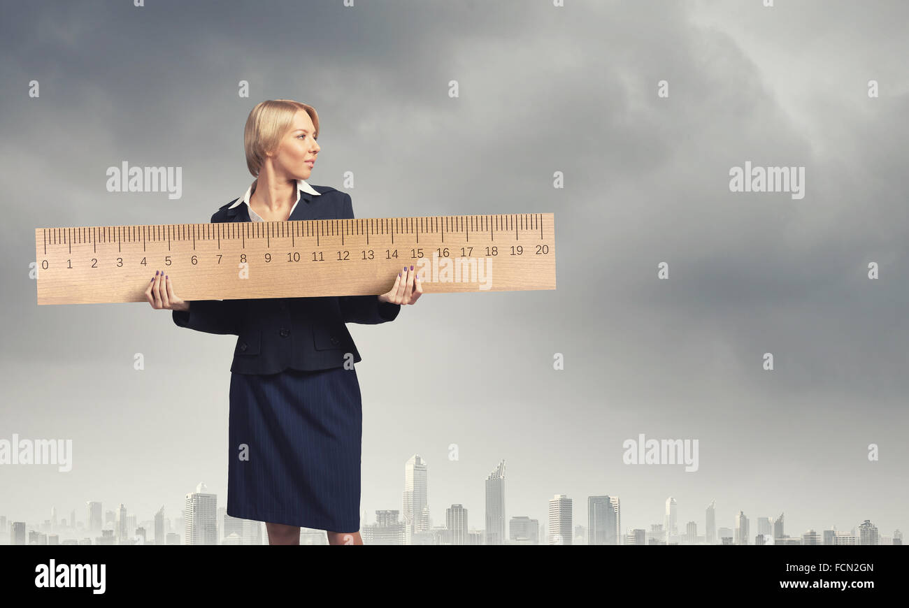 Young businesswoman measuring something with big ruler Stock Photo - Alamy