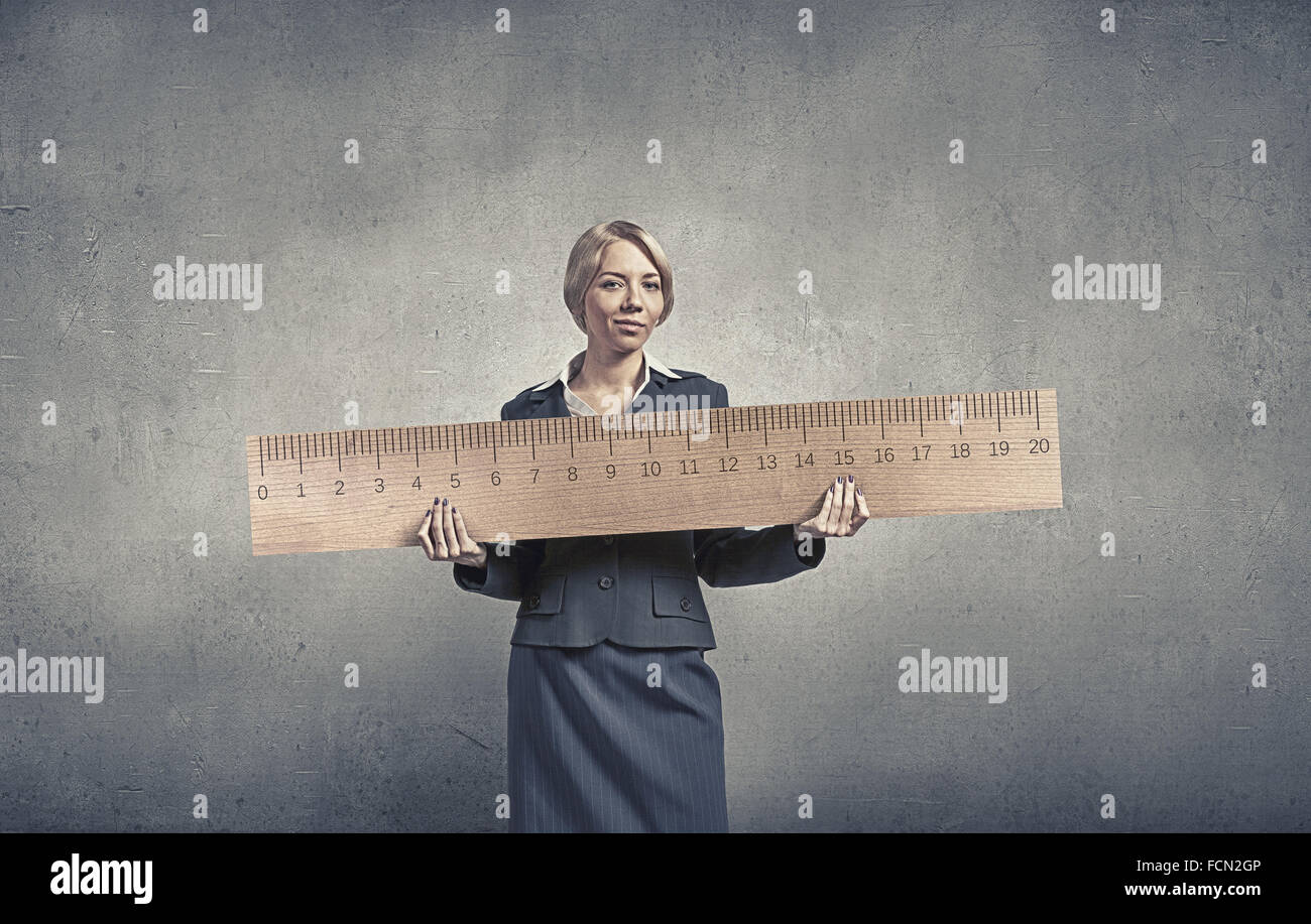 Young businesswoman measuring something with big ruler Stock Photo - Alamy