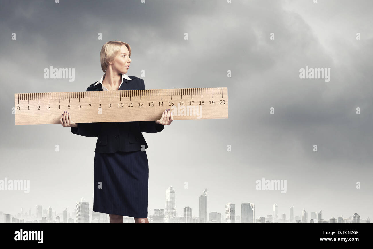 Young businesswoman measuring something with big ruler Stock Photo - Alamy