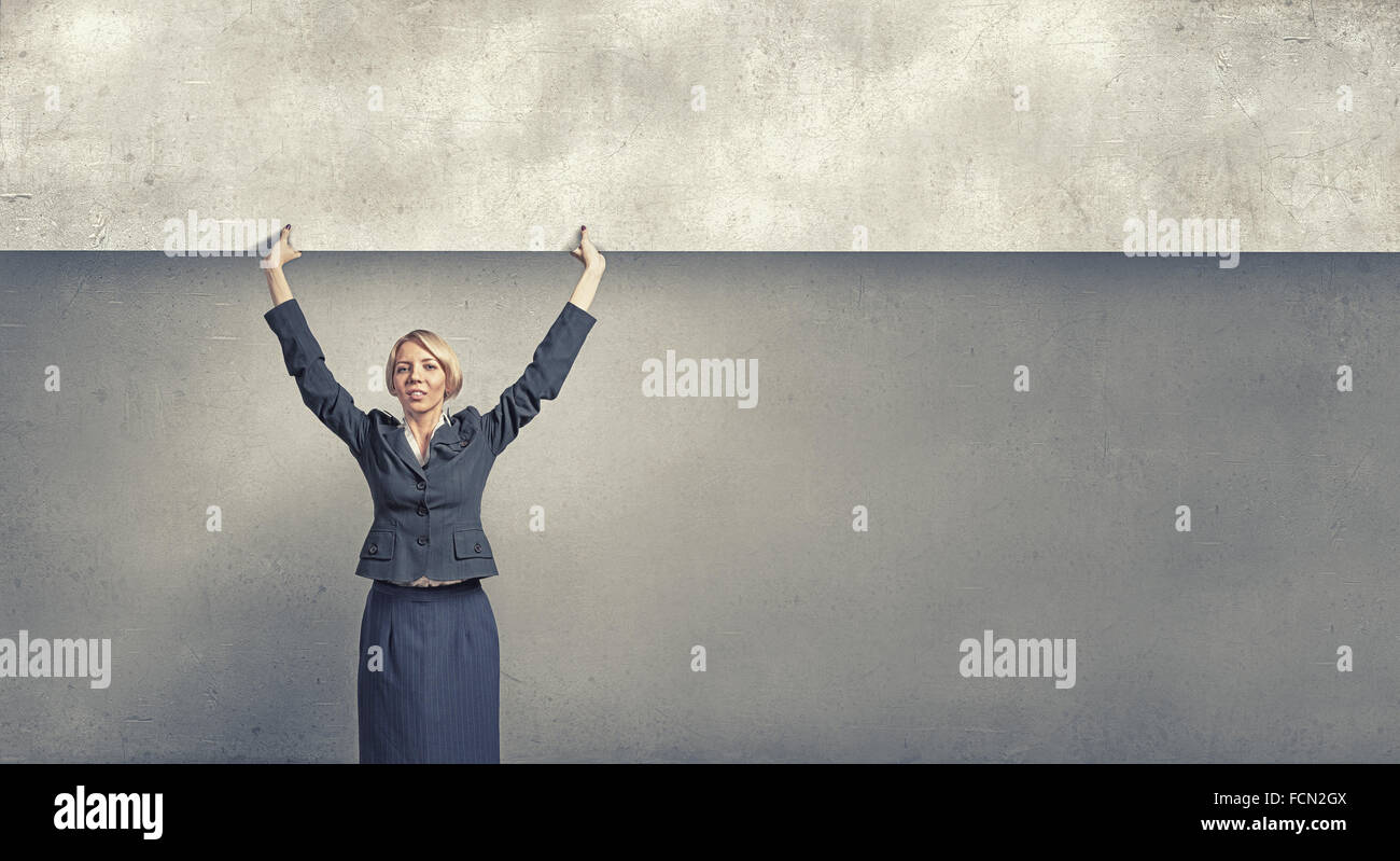 Young businesswoman lifting cement banner above head Stock Photo - Alamy