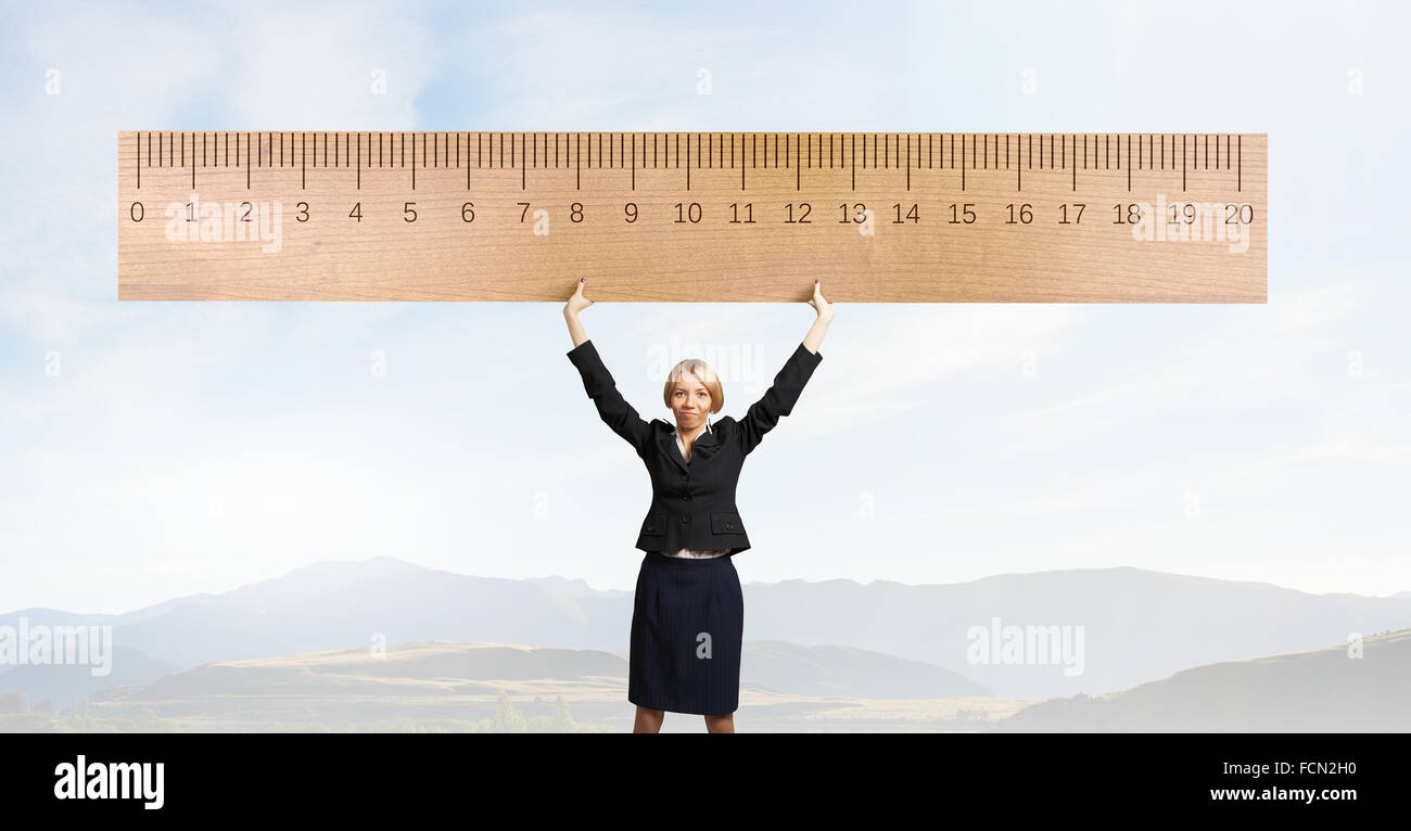 Young businesswoman measuring something with big ruler Stock Photo - Alamy