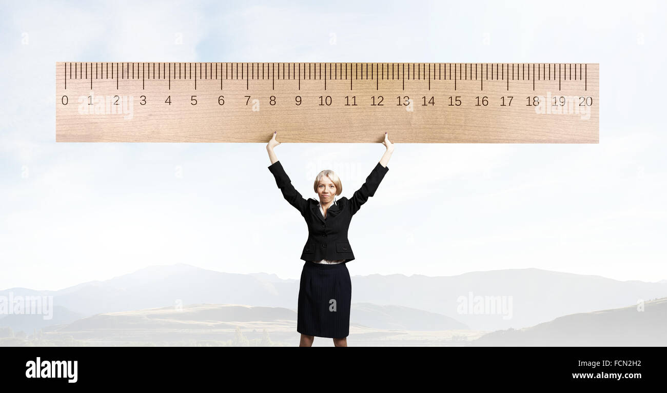 Young businesswoman measuring something with big ruler Stock Photo - Alamy