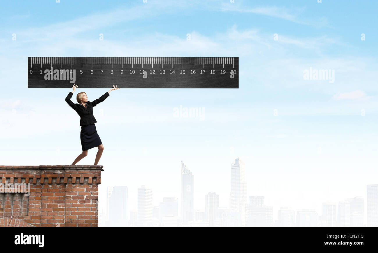 Young businesswoman measuring something with big ruler Stock Photo - Alamy