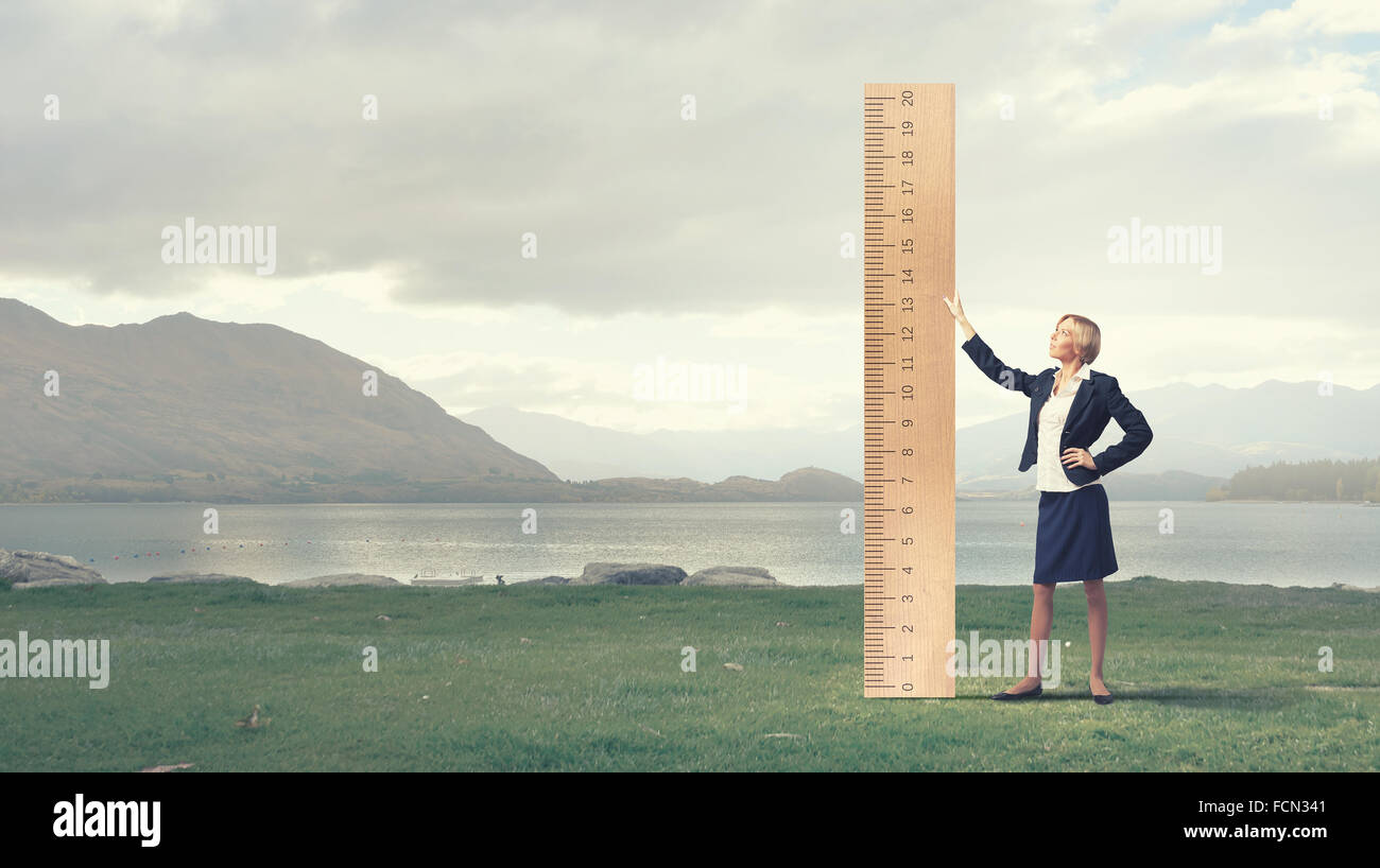 Young businesswoman measuring something with big ruler Stock Photo - Alamy