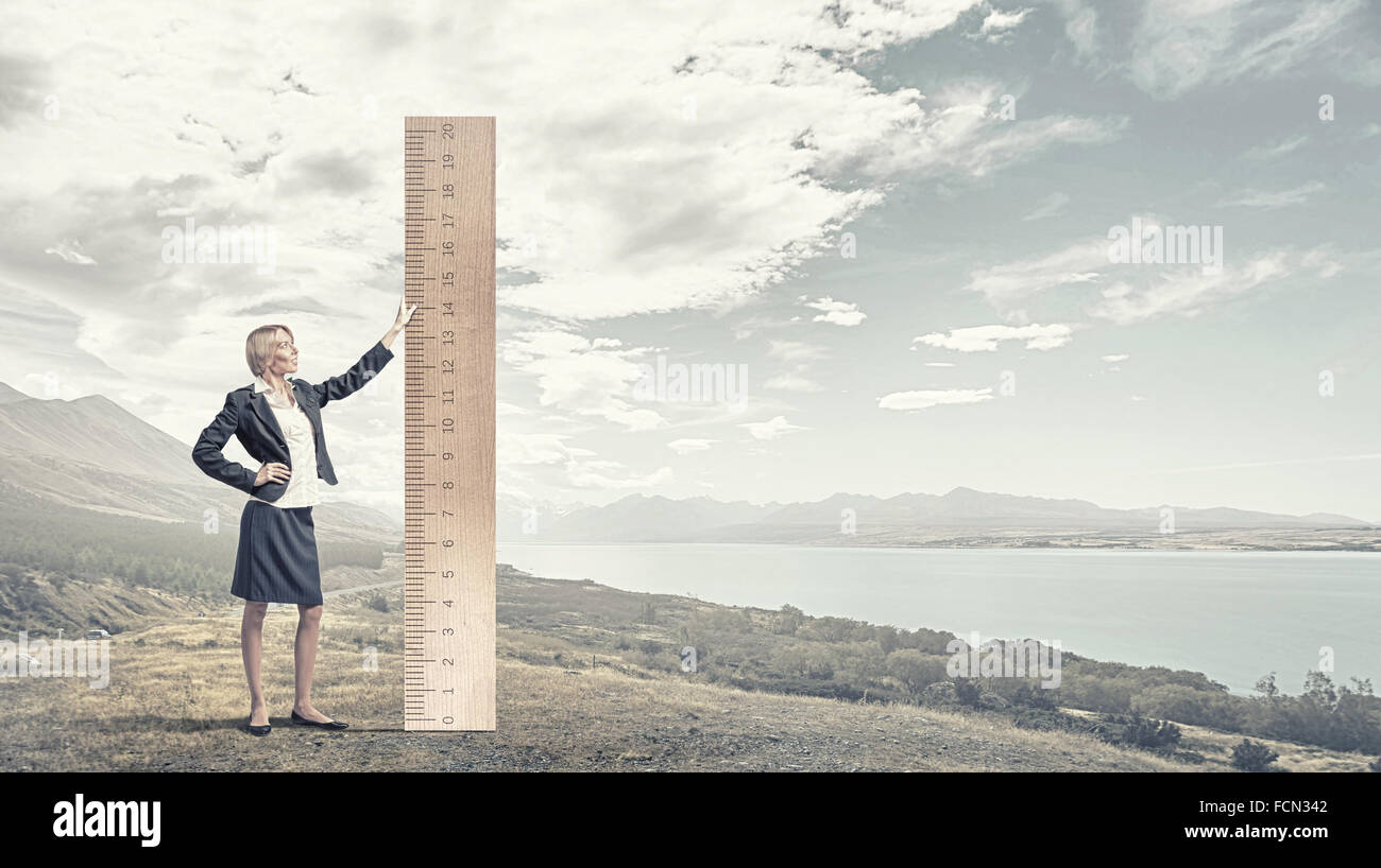 Young businesswoman measuring something with big ruler Stock Photo - Alamy