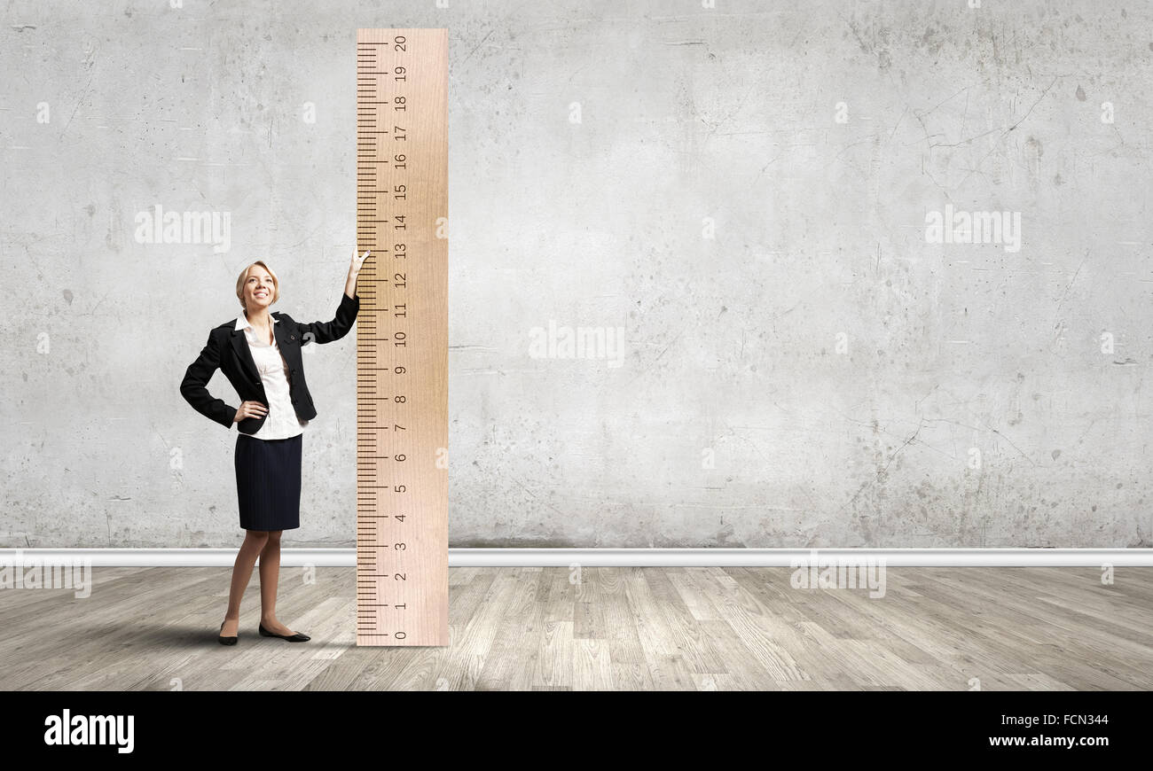 Young businesswoman measuring something with big ruler Stock Photo - Alamy
