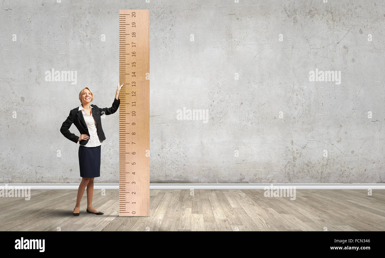 Young businesswoman measuring something with big ruler Stock Photo - Alamy