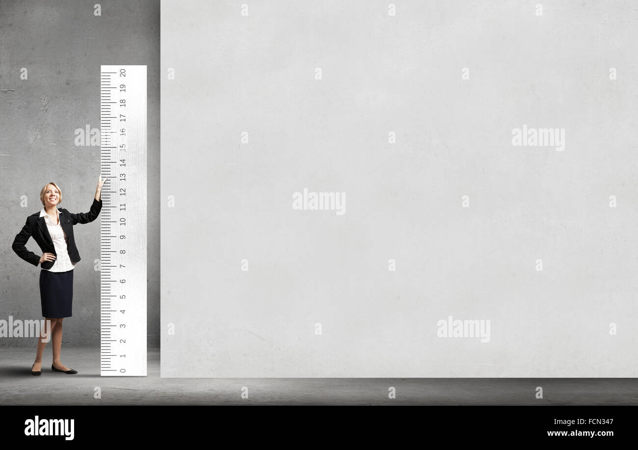 Young businesswoman measuring something with big ruler Stock Photo - Alamy