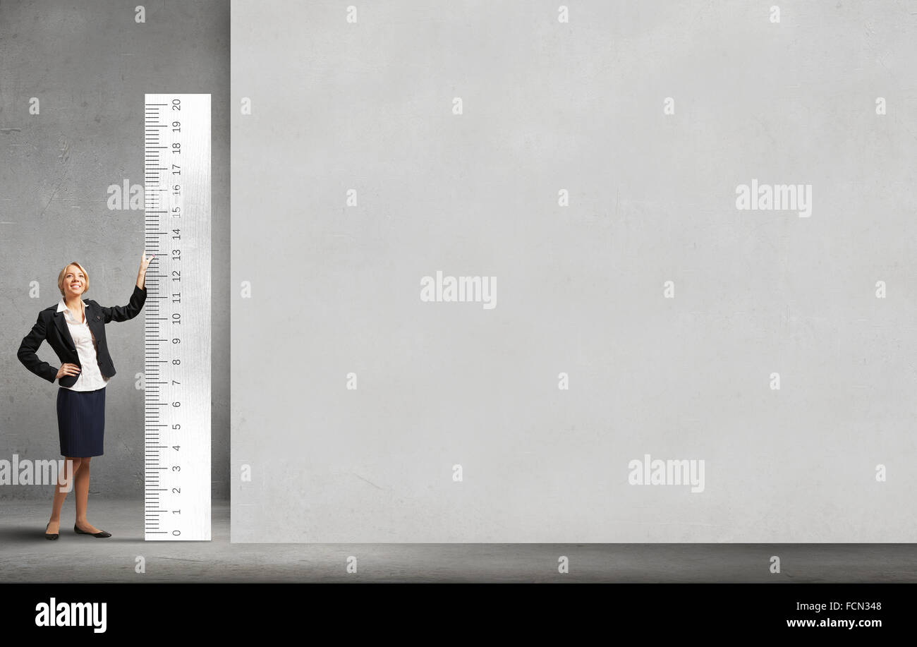 Young businesswoman measuring something with big ruler Stock Photo - Alamy
