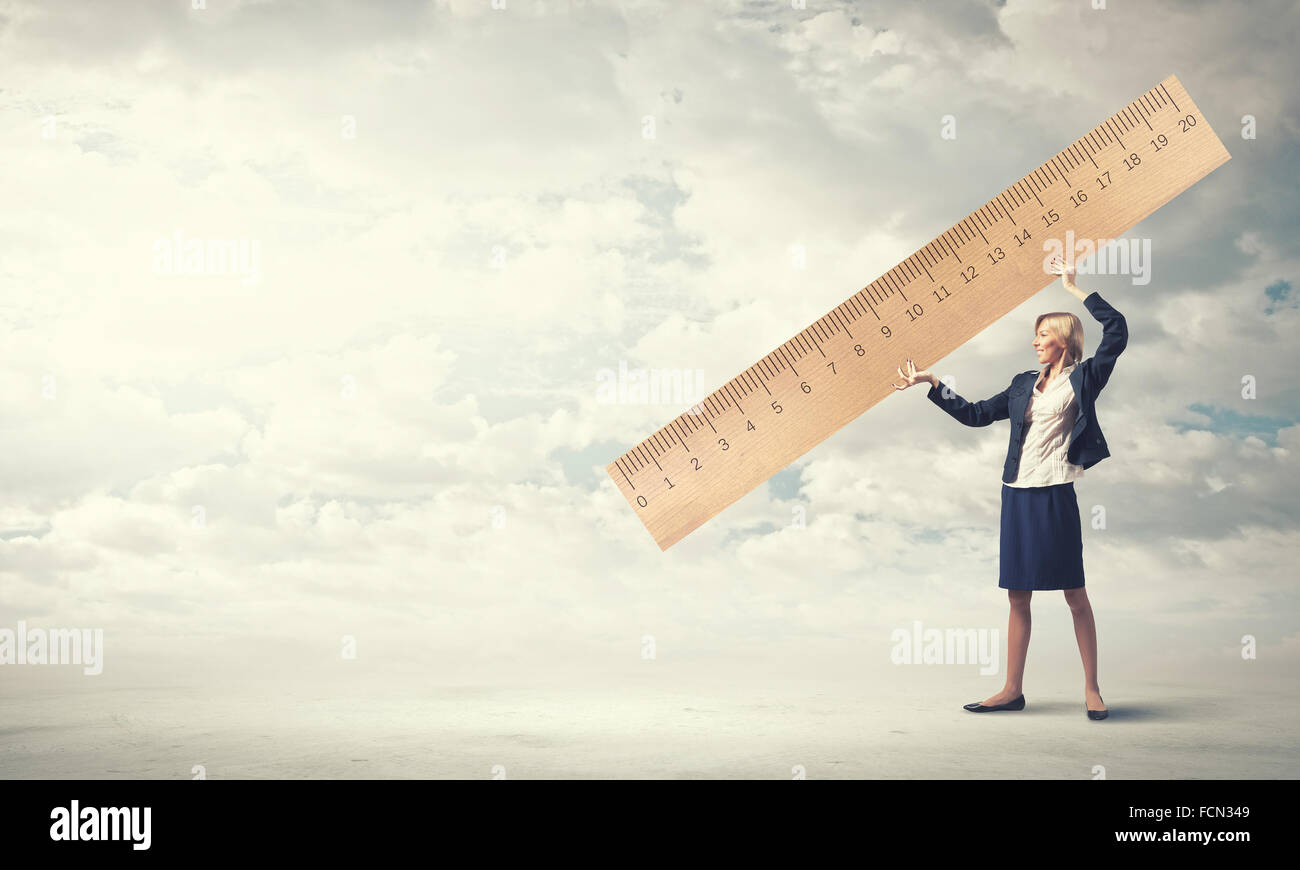Young businesswoman measuring something with big ruler Stock Photo - Alamy