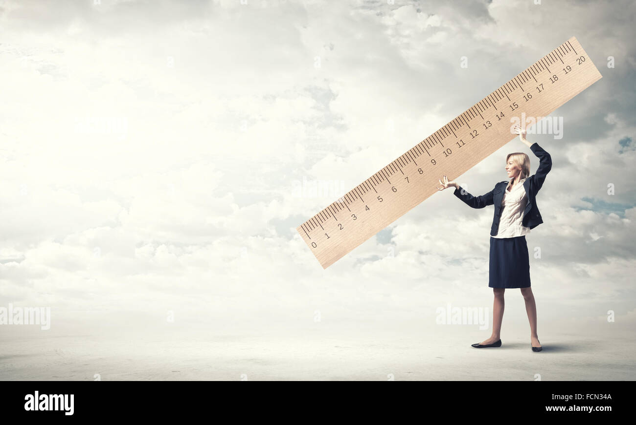Young businesswoman measuring something with big ruler Stock Photo - Alamy