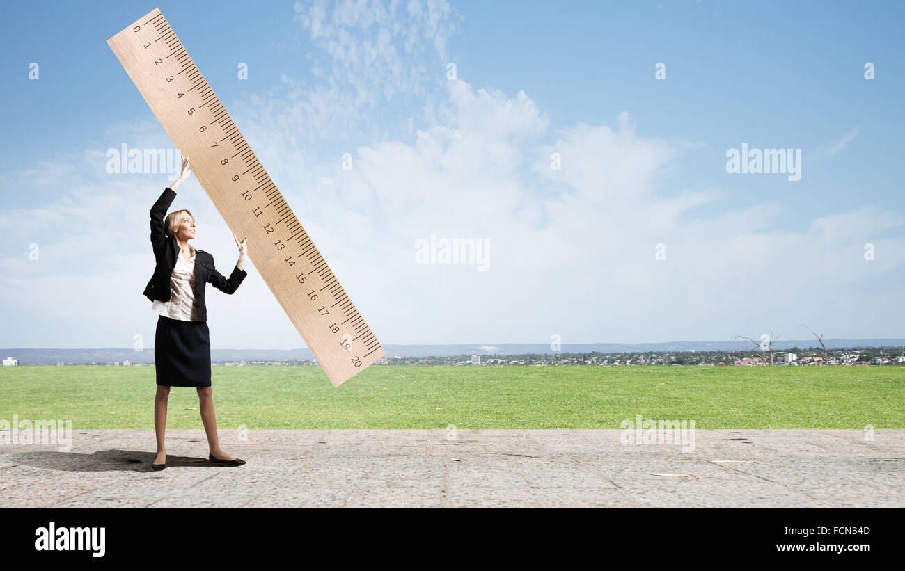 Young businesswoman measuring something with big ruler Stock Photo - Alamy
