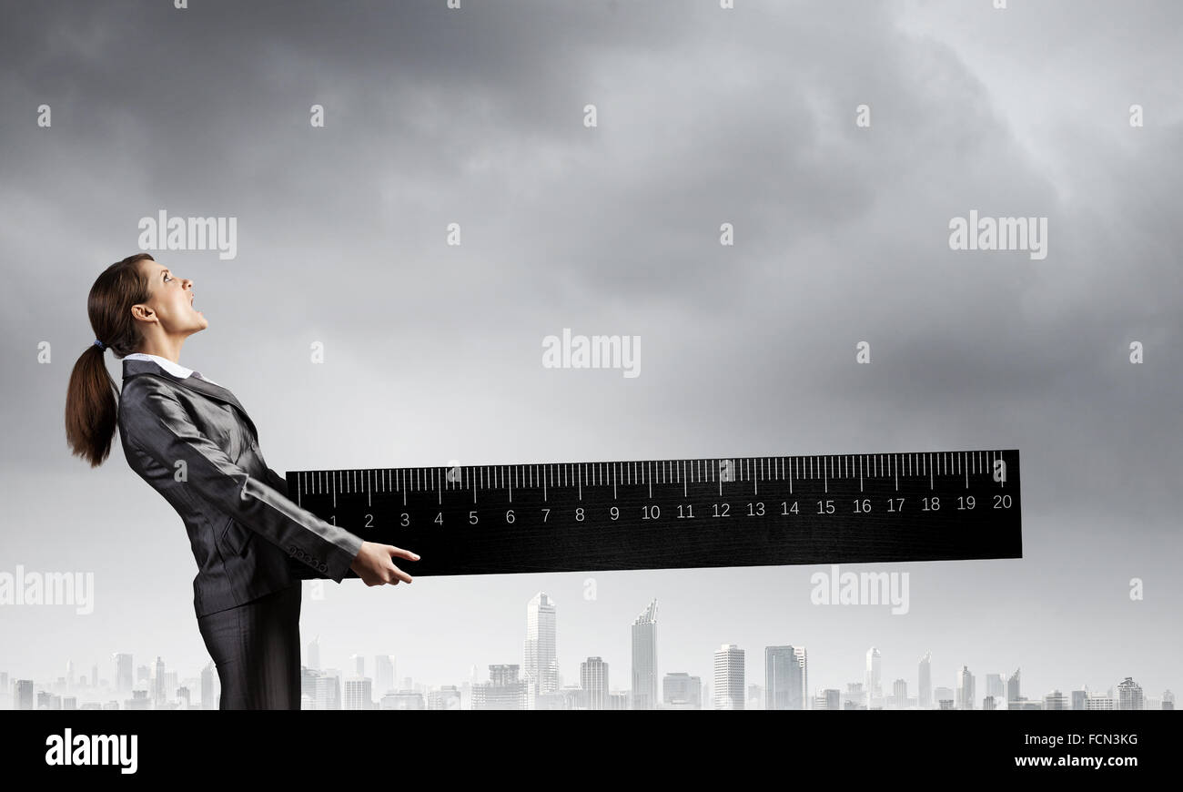 Young businesswoman carrying big ruler in hands Stock Photo - Alamy