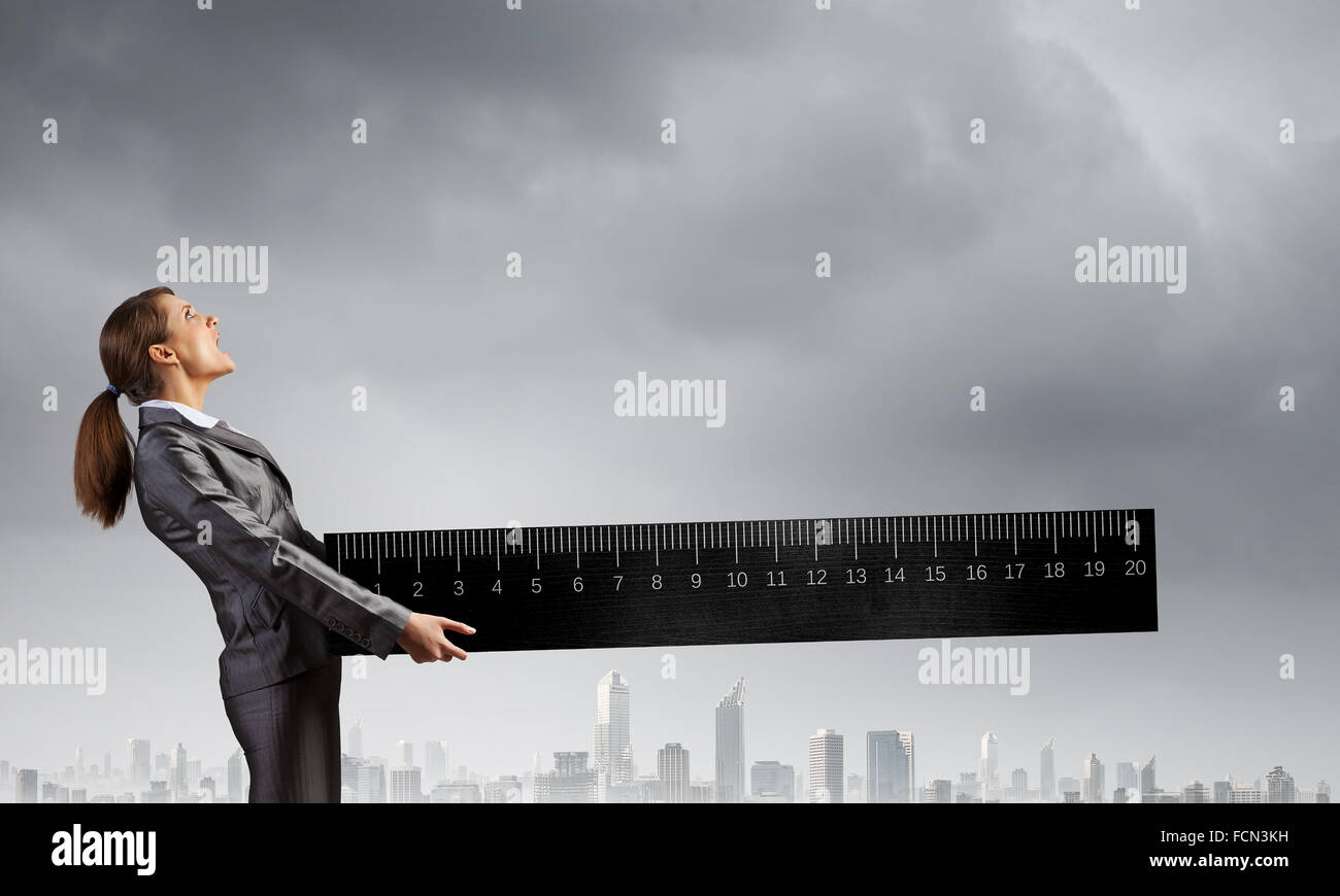 Young businesswoman carrying big ruler in hands Stock Photo - Alamy