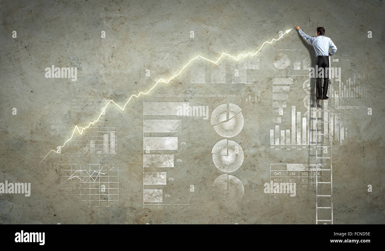 businessman standing on ladder drawing diagrams and graphs Stock Photo ...