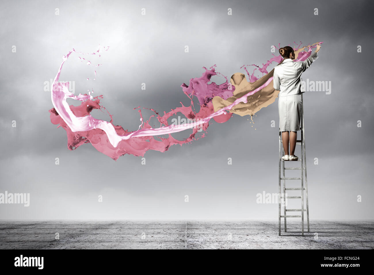 Young woman standing on ladder drawing splashes with finger Stock Photo ...