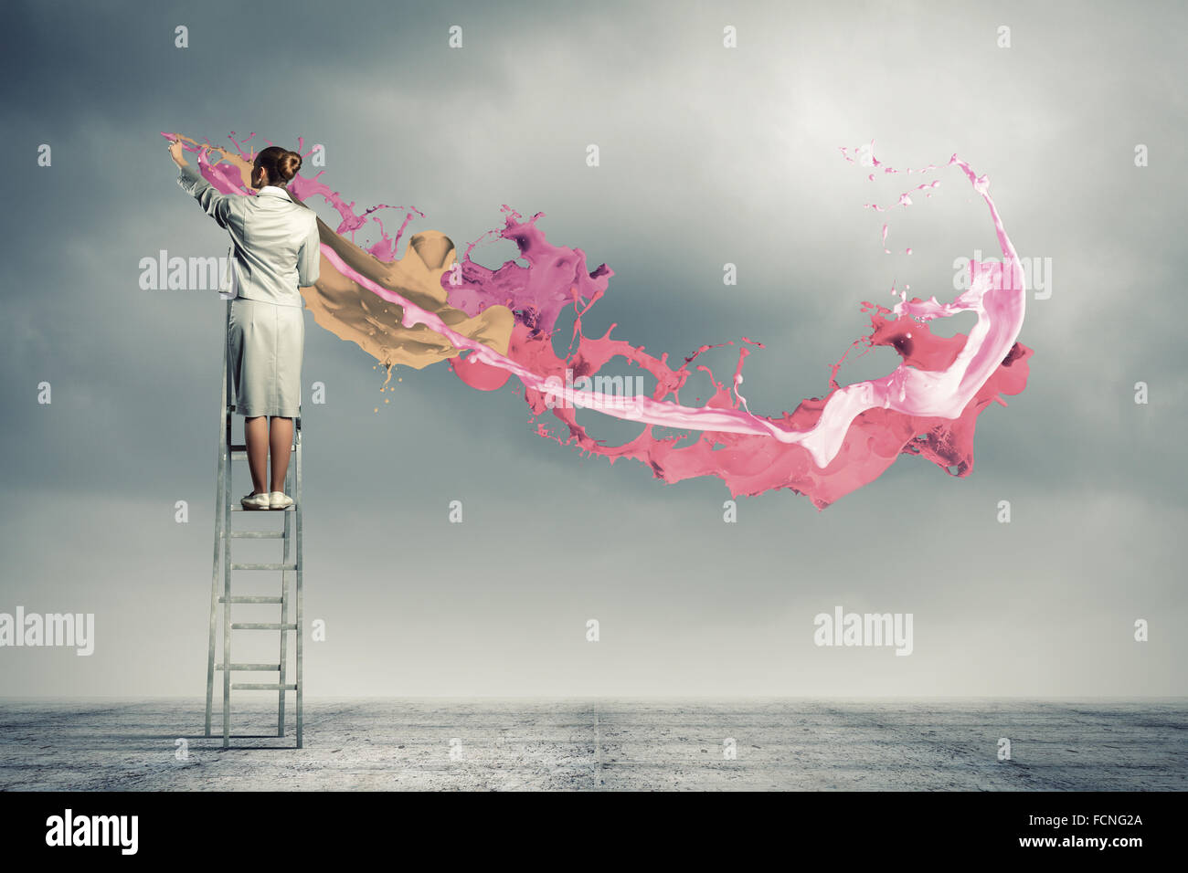 Young woman standing on ladder drawing splashes with finger Stock Photo ...
