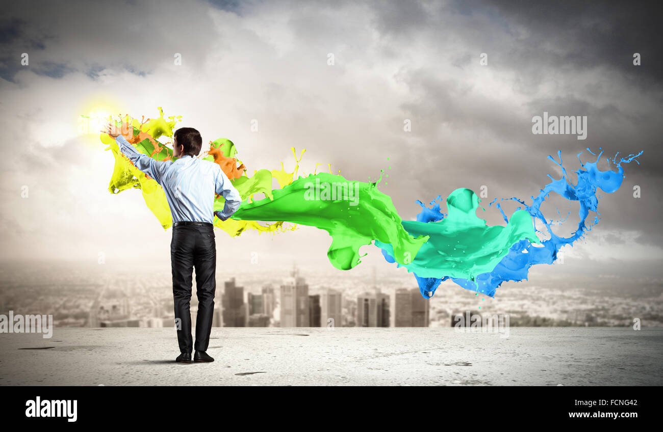 young man standing with back painting splashes against city background ...