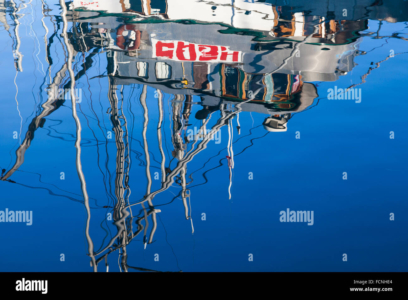 Reflection of a commercial fishing boat on calm water with a blue sky ...