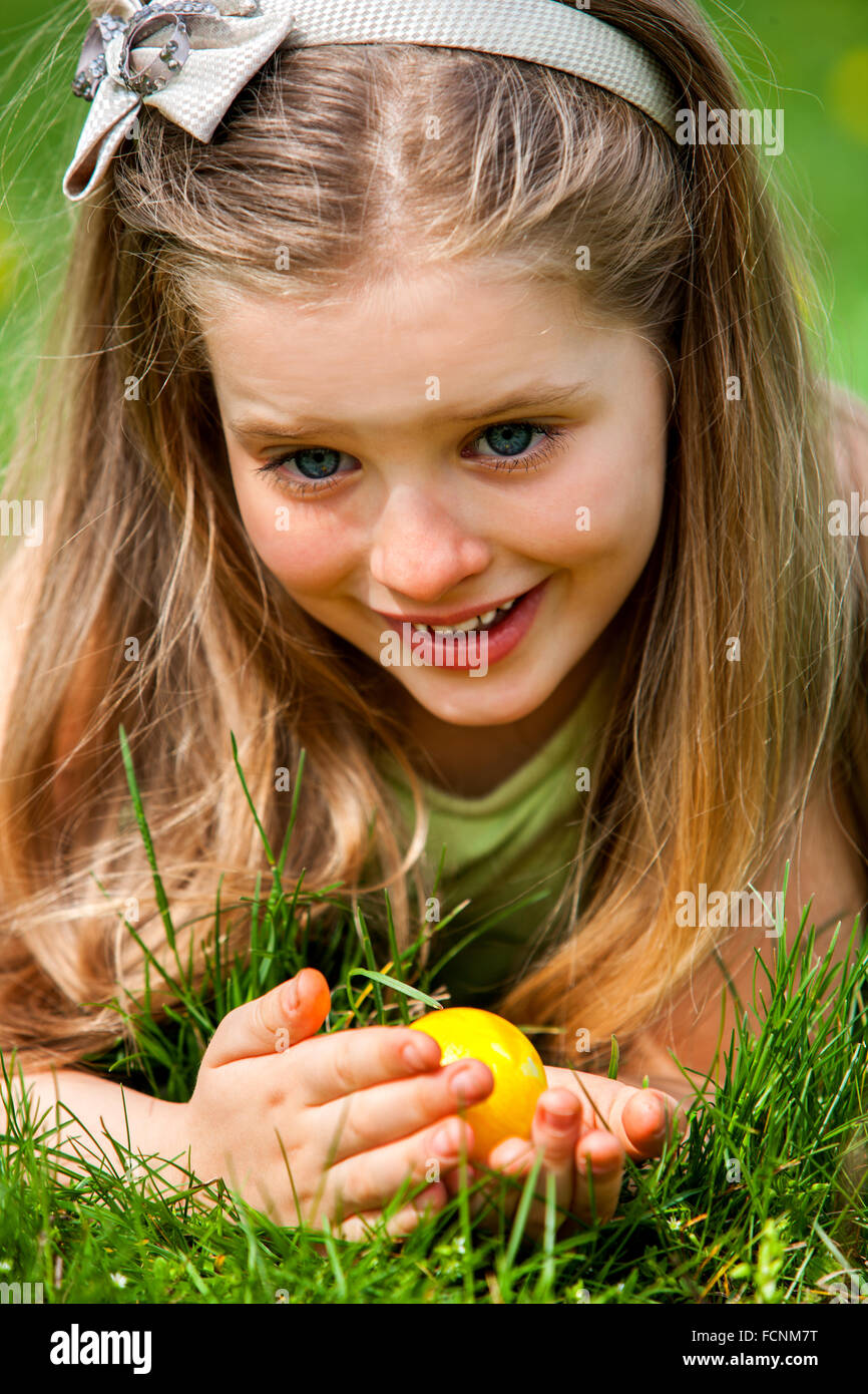 Child with bow on head find easter egg outdoor Stock Photo - Alamy