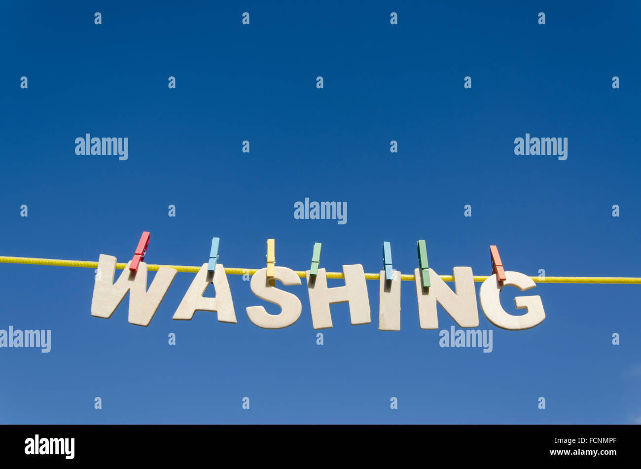 The word washing (laundry) is strung on pegs from a clothesline with a ...