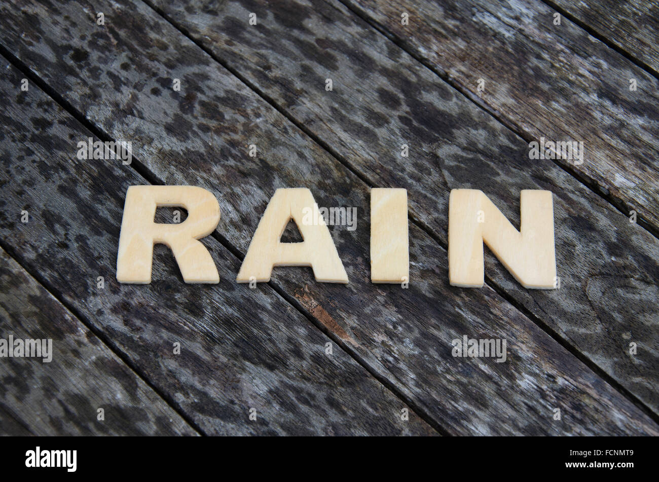 Letters forming the word rain laid on a outside timber deck in the rain ...