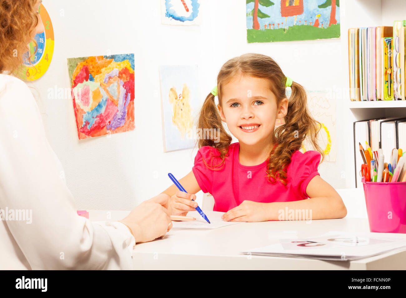 Preschool teacher helping pupil with class work Stock Photo - Alamy