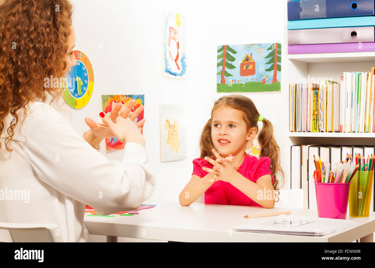 Schoolgirl repeating fingers exercises to teacher Stock Photo - Alamy