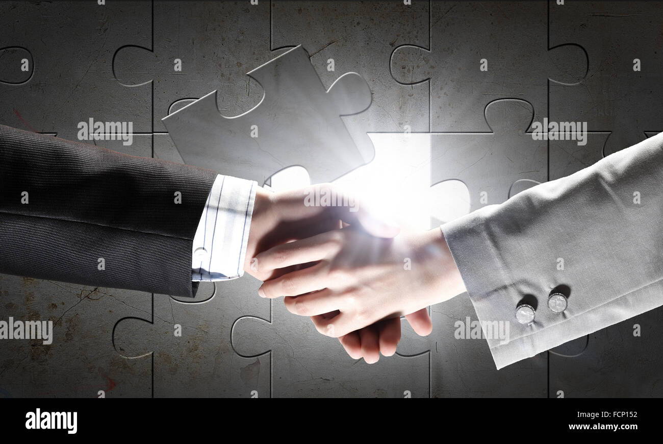 Close up of business handshake with puzzle elements at background Stock ...