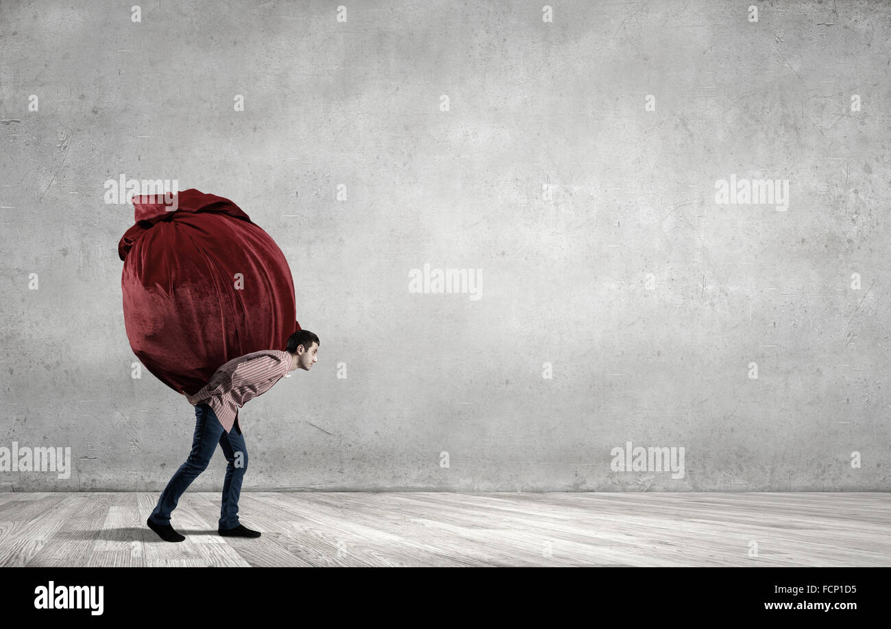 Young man in casual carrying heavy red bag Stock Photo - Alamy