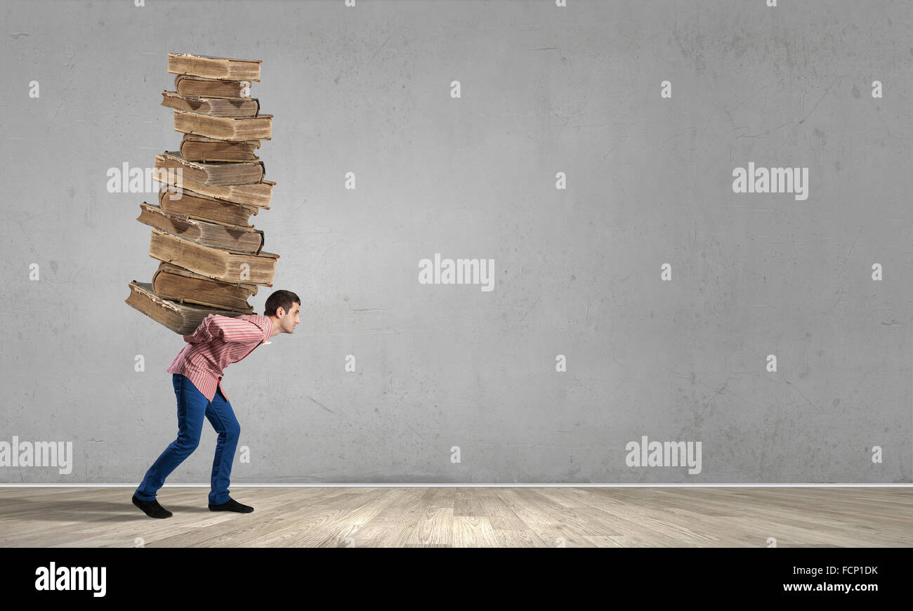 Young guy carrying pile of old books Stock Photo - Alamy