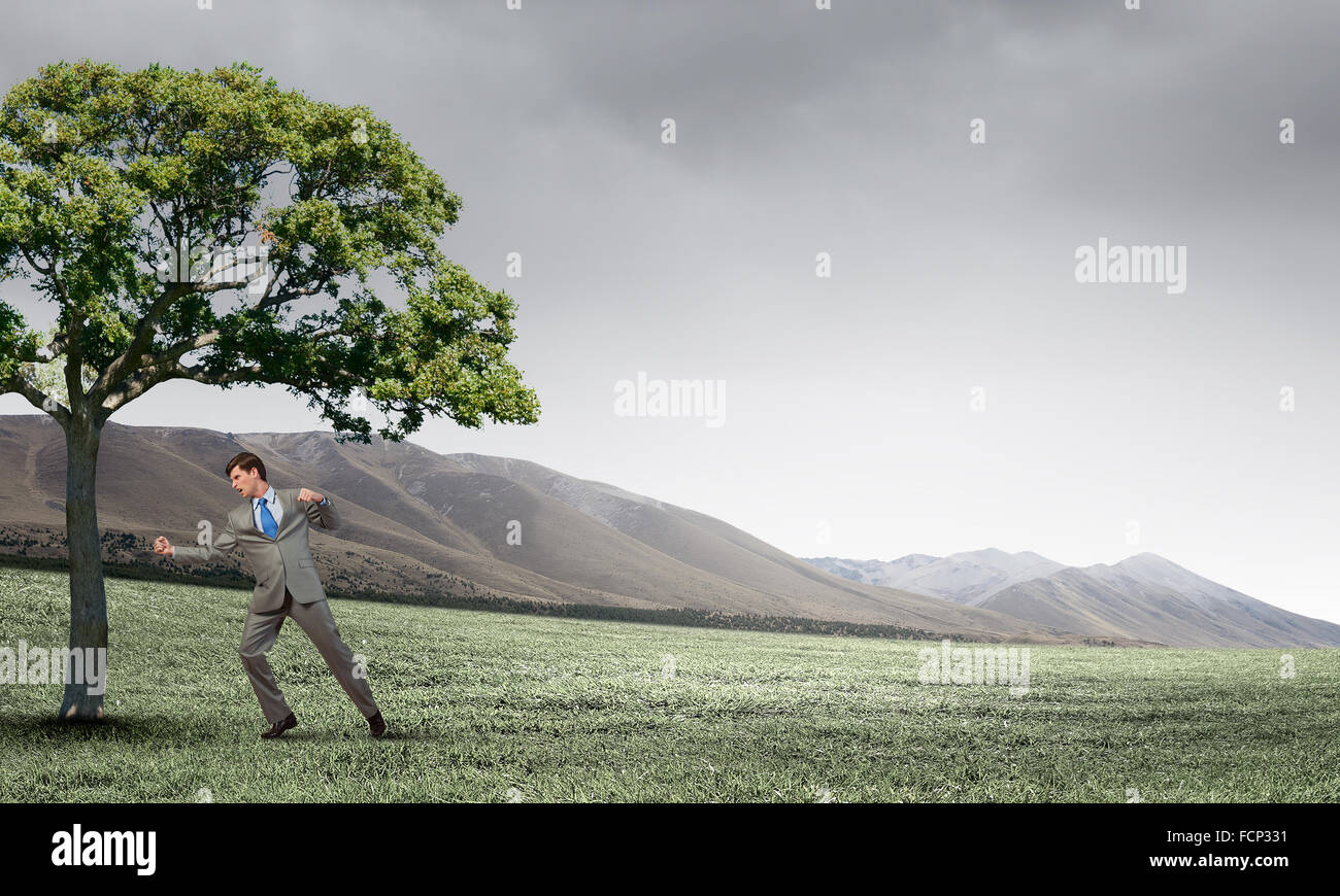 Young businessman in anger fighting with green tree Stock Photo - Alamy