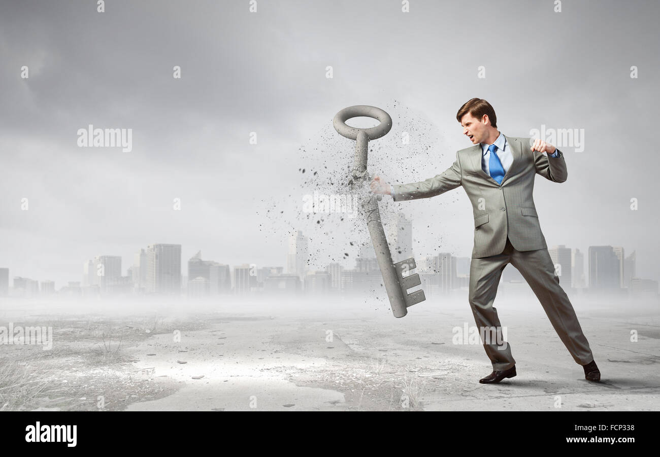 Angry businessman crashing stone key with punch Stock Photo - Alamy