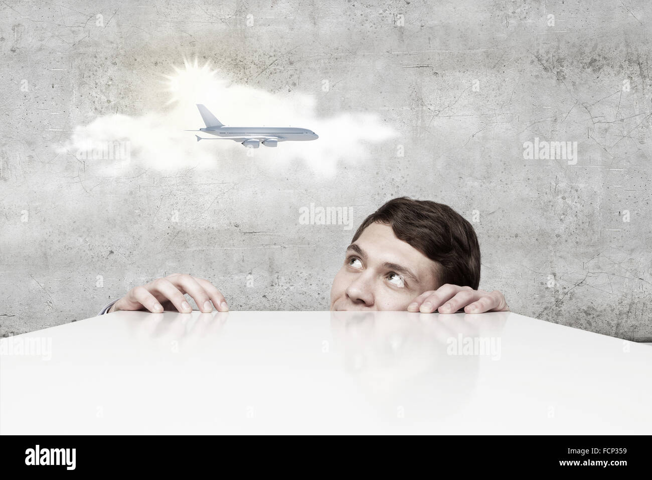 Young man looking from under table on flying airplane Stock Photo - Alamy