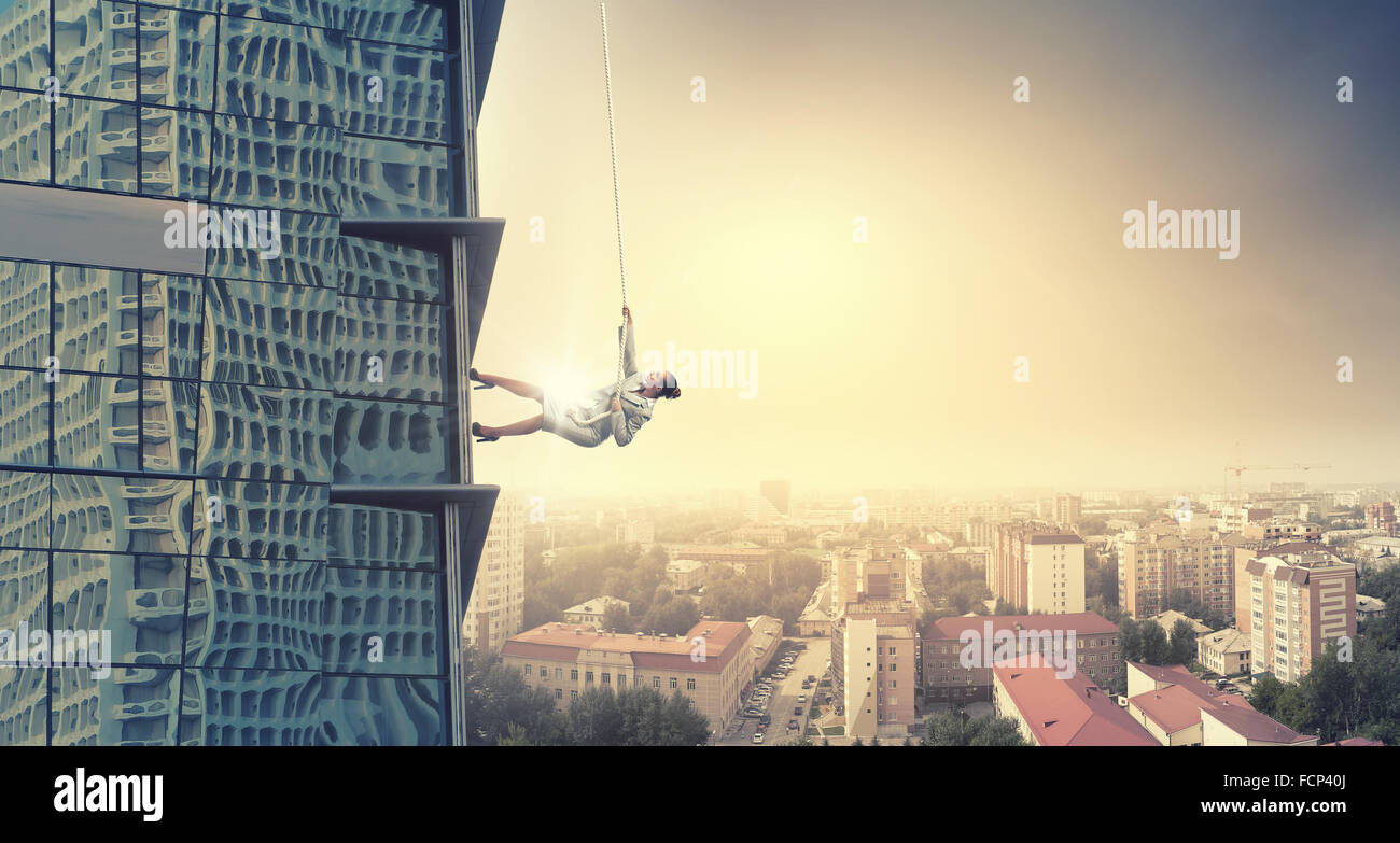 Determined businesswoman climbing building with help of rope Stock ...