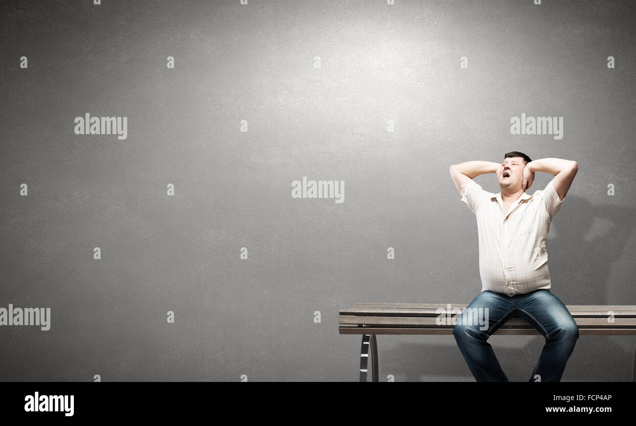 Fat man sitting on bench closing ears with hands hi-res stock ...