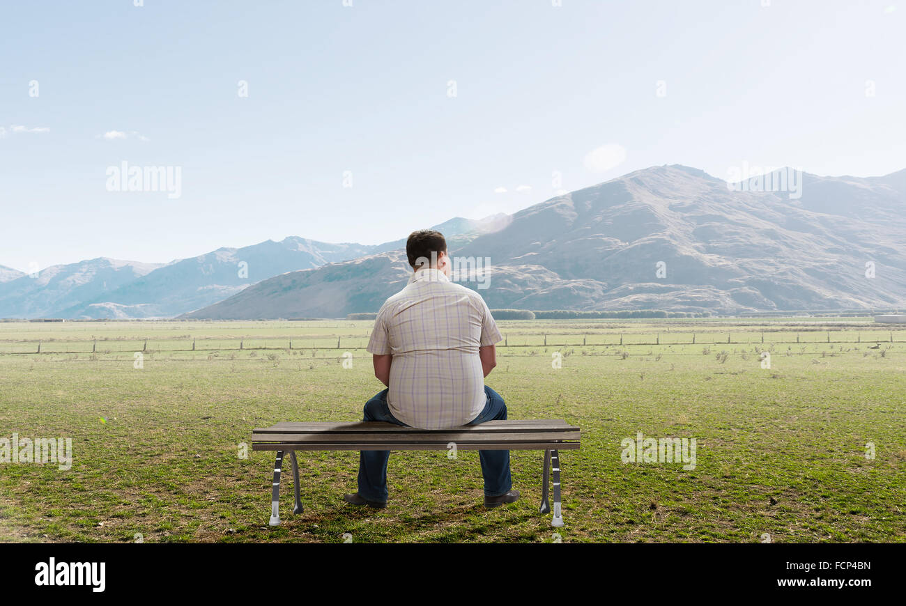 Fat man sitting on bench with his back and looking away Stock Photo - Alamy