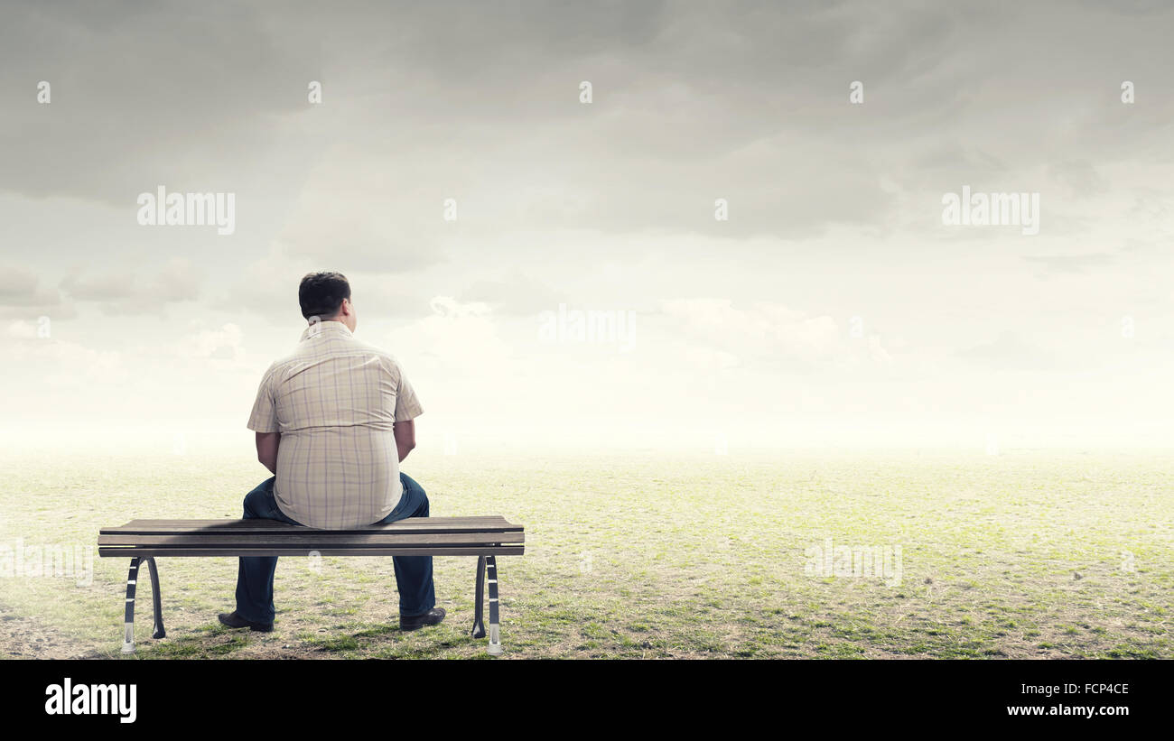 Fat man sitting on bench with his back and looking away Stock Photo - Alamy